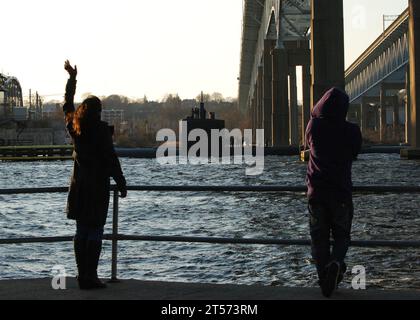 US Navy Family members wave goodbye as the amphibious assault ship USS ...