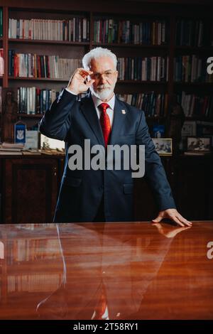 Experienced University Rector Posing Confidently with Books in Library ...