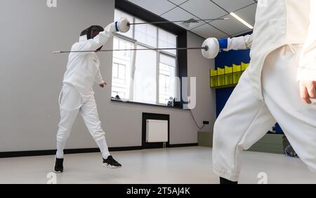 Children lunge on swords. A child in a class at a fencing school Stock ...