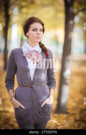 In the enchanting autumn forest, a brunette girl stands, captivated by ...