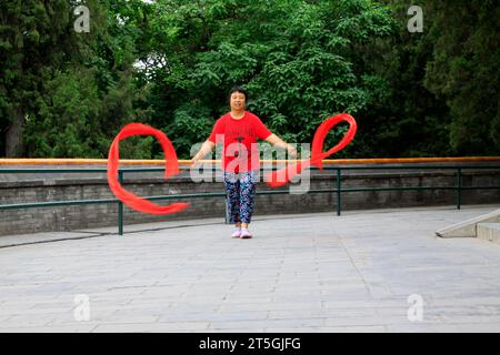 BEIJING - MAY 23: lady was Waving red silk cloth in the Beihai Park，on ...