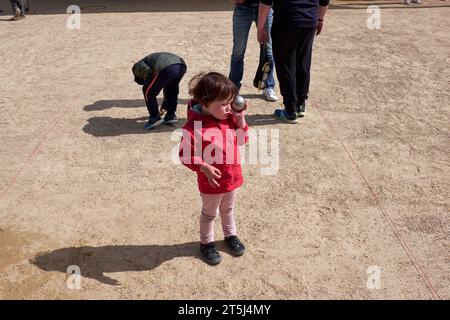 Little girl with a steel ball at a boules game ground Stock Photo - Alamy