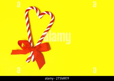 Two Christmas candy canes overlapping to form a heart and a red bow on ...