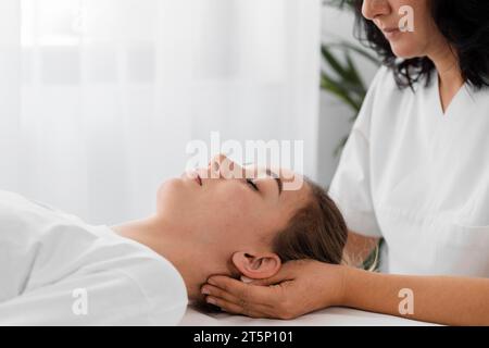Female osteopathist treating patient by massaging her face Stock Photo ...