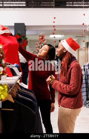 Employee presenting clothes to client in outlet store, showing multiple ...
