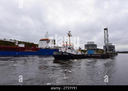 Tugboat towing a pontoon with offshore installation in the Kiel Canal ...