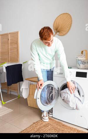 Young man putting laundry into washing machine at home Stock Photo - Alamy