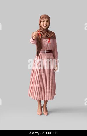 Beautiful Muslim woman with red ribbons on grey background. AID ...