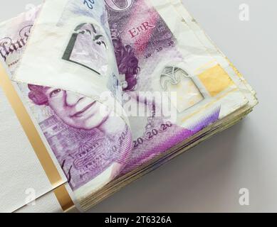 A bundled wad of british pound banknotes on an isolated light ...