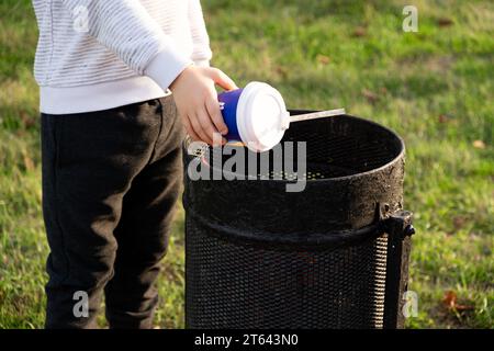 A child throws a plastic cup in the trash. Garbage recycling and ...