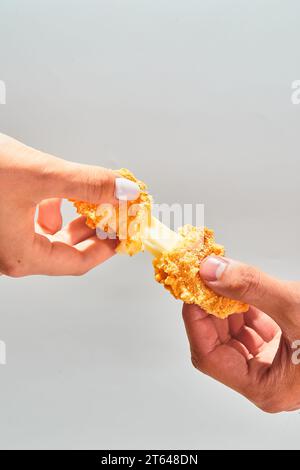 Crispy cheese fried breaded mozzarella cheese sticks stretch two hands ...