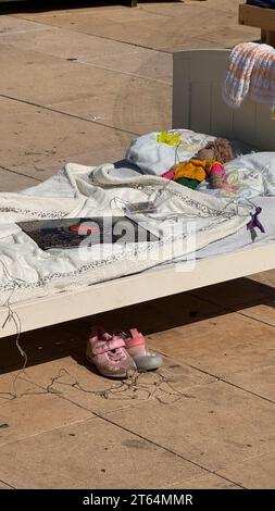 An art installation of "empty beds" and a "hostage table" in front of ...