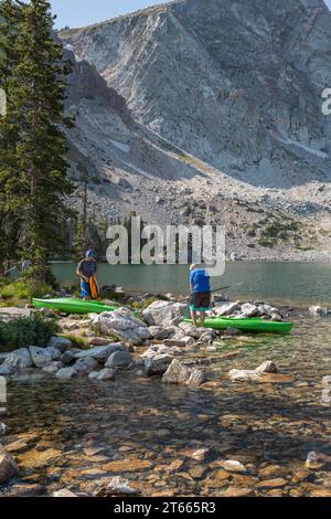 Two young men prepare for kayaking along the rock shoreline of Lake ...