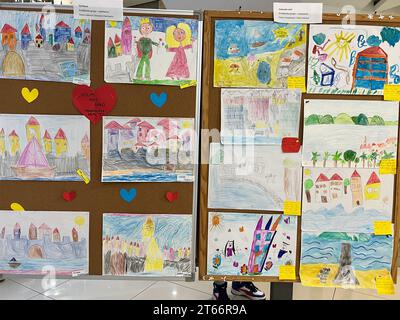 Colorful children drawings hang on a stand. Many children drawings hang ...