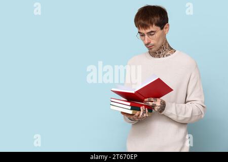 Young tattooed man with books reading on pink background Stock Photo ...