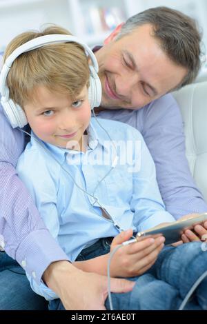 Man cuddling child listening to headphones Stock Photo - Alamy