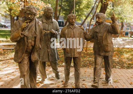 A bronze statue of five men speaking to each other and standing in ...