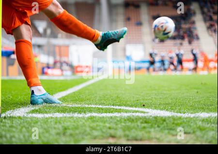 Footballer takes the corner. Detail of player's legs and the ball ...