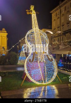 Violin with Christmas decor and music note sheets on color background ...