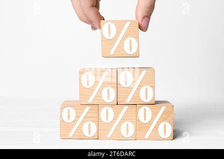 Woman building pyramid of cubes with percent signs on light blue ...