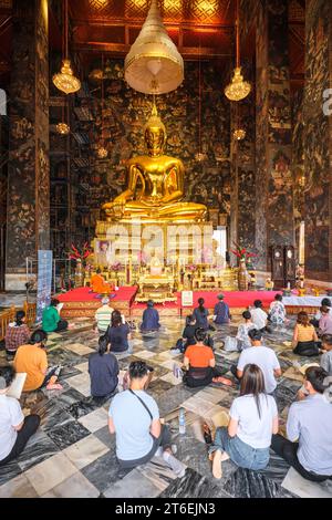 Worshippers crowd the inside of the temple, sitting on the ground and ...