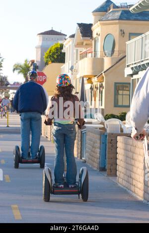 Visitors to the boardwalk at Newport Beach, California ride the segway ...