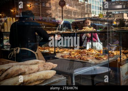 Customers order pastries and other baked goods in the window of ...