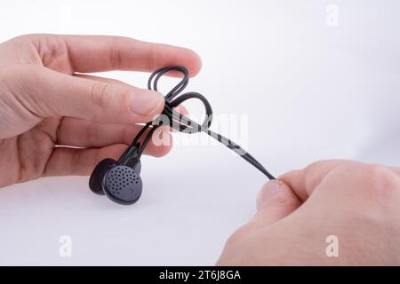 Hand holding a black earphone on a white background Stock Photo - Alamy
