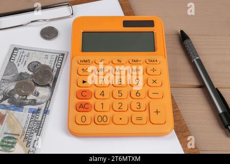 Orange calculator, money, clipboard with paper sheet, pen and glasses ...
