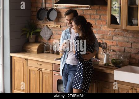 Happy young couple drinking hot beverage in kitchen Stock Photo - Alamy
