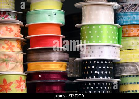 Colourful rolls of patterned and plain textile ribbons in haberdashery ...