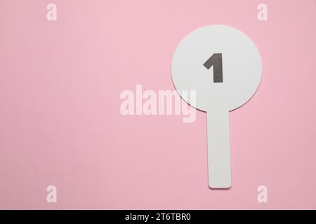 Auction paddle with number 4 on pink background, top view. Space for ...