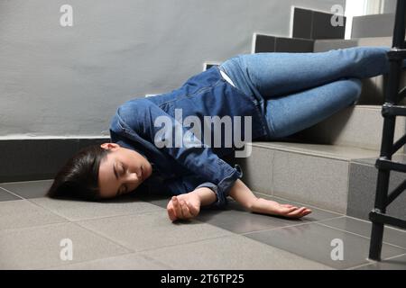 Unconscious woman lying on floor after falling down stairs indoors ...