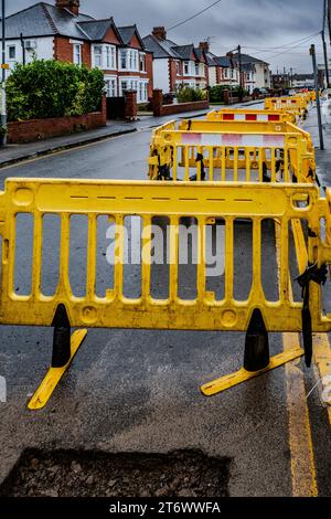 Pipe laying roadworks in Cardiff. Bright yellow safety barriers protect ...