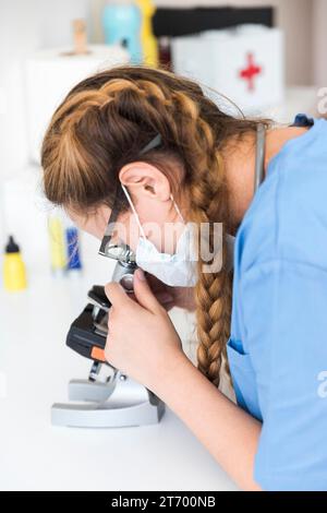 female laboratory assistant looking through a microscope research ...