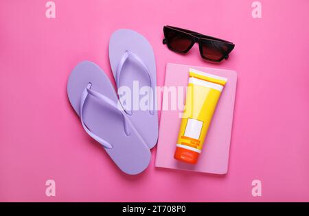 Stylish pink flip flops, sunscreen and sunglasses on yellow background ...