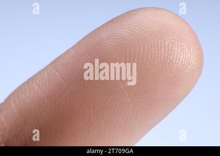 Finger with friction ridges on light blue background, macro view Stock ...