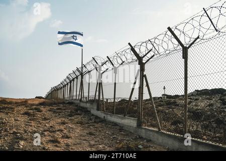 View of israeli flag behind barbed wire against cloudy sky. border post ...