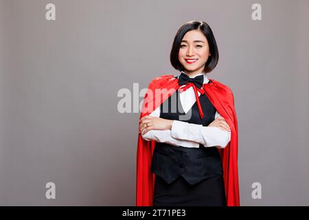 Receptionist with arms crossed wearing red superman cloak, representing ...