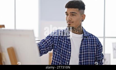 Passionate, tattooed latin man artist immersed in drawing his portrait ...