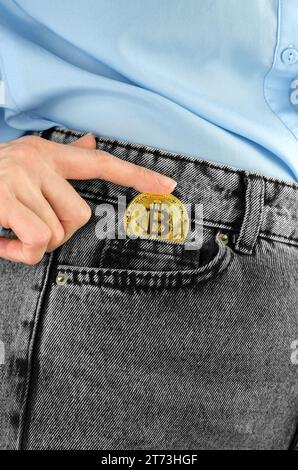 A woman's hand puts a golden bitcoin in a jeans pocket, close-up Stock ...