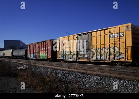 Freight train with yellow hopper cars on railway station platform under ...