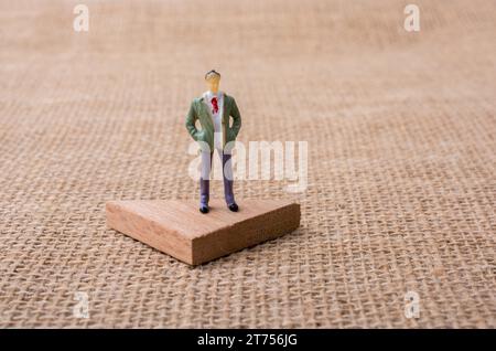 Man figurine standing on a triangle piece of wood Stock Photo - Alamy