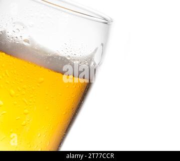 detail of tilted glass of fresh beer with drops on white background ...