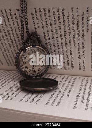 Silver pocket clock and book on white table Stock Photo - Alamy