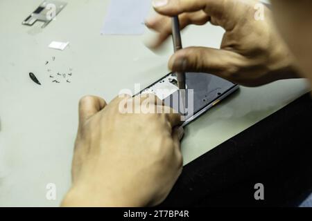 electronics repair service technician disassembling smartphone for ...