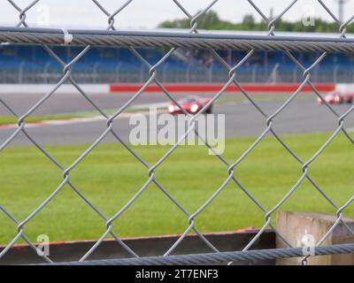 blurred racing cars and stands seen through in focus wire fence Stock ...