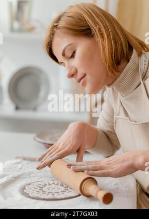 A girl is using the rolling pin to roll out the dough on the table ...