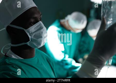 African american male surgeon applying drip in operating theatre at ...