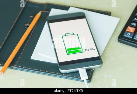 Mobile smart phones charging on wooden desk Stock Photo - Alamy